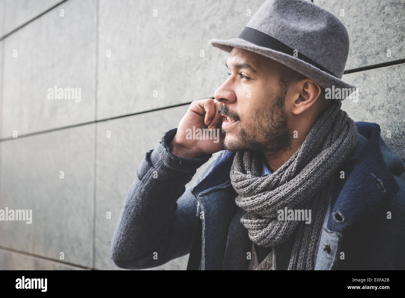 Close up of businessman leaning against wall talking on smartphone ...