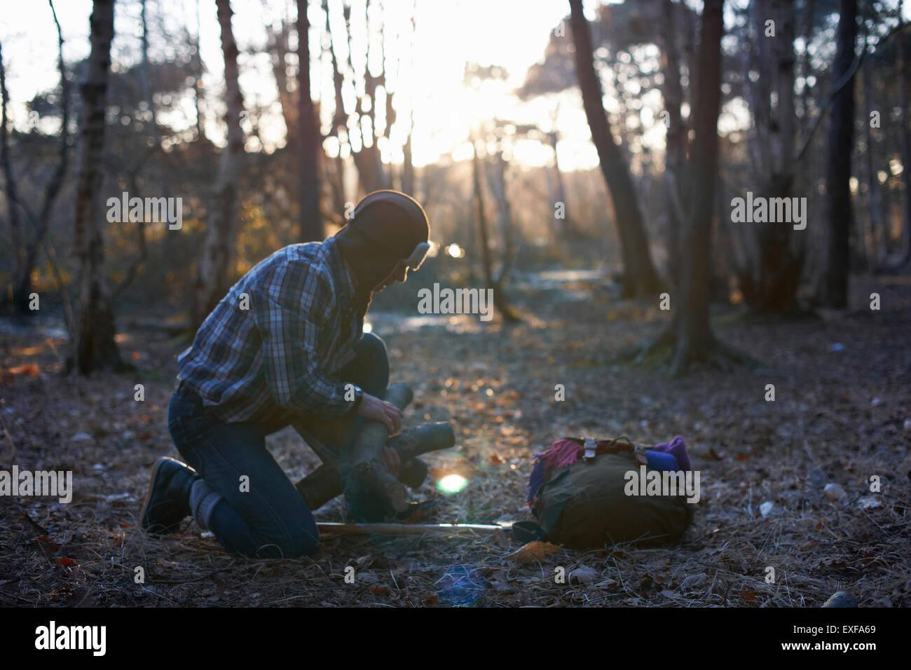 Mature male backpacker stacking logs for campfire in forest Stock Photo ...