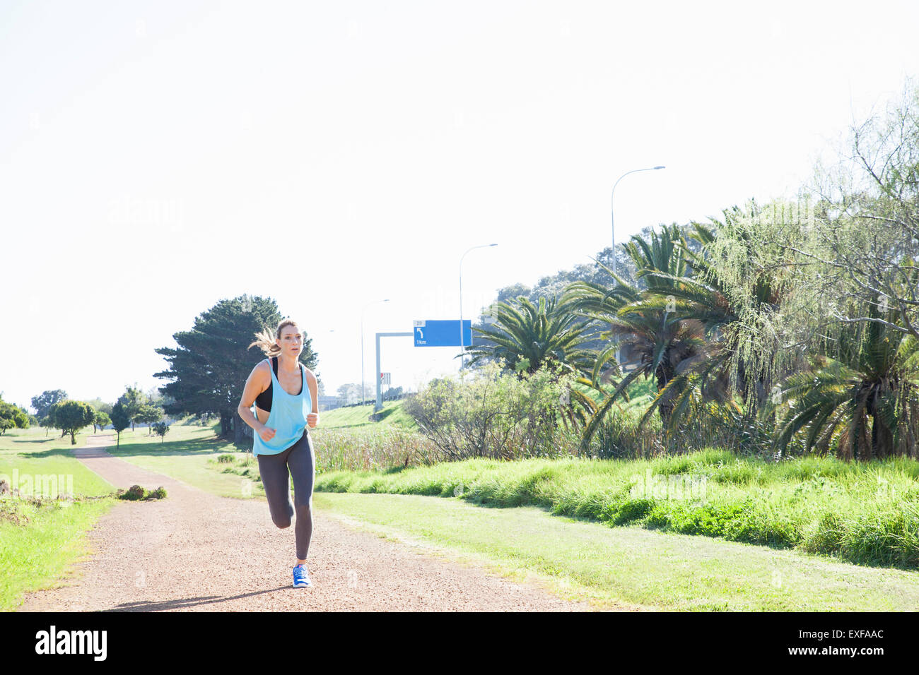 Mid adult woman running on dirt track in park Stock Photo - Alamy