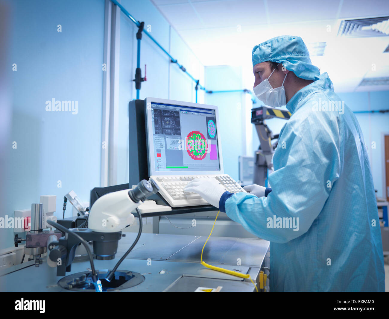 Electronics worker checking silicon wafer in clean room laboratory ...