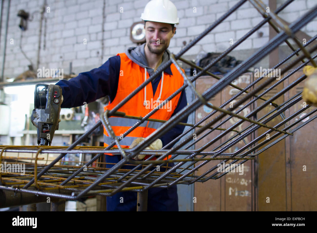 Factory worker attaching steel mesh at concrete reinforcement factory ...