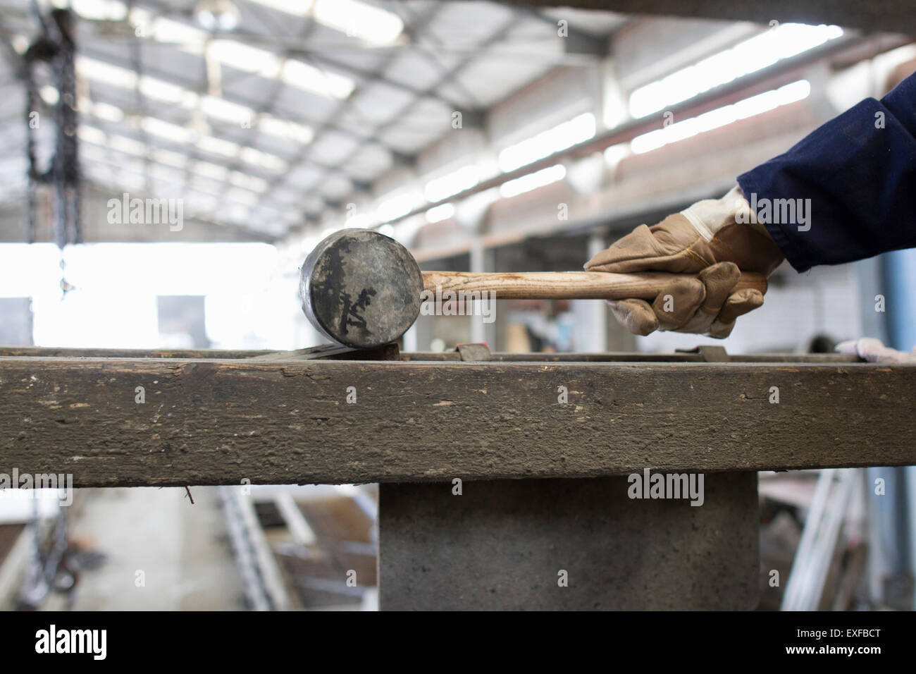 Close up of factory workers hand with rubber hammer in concrete ...