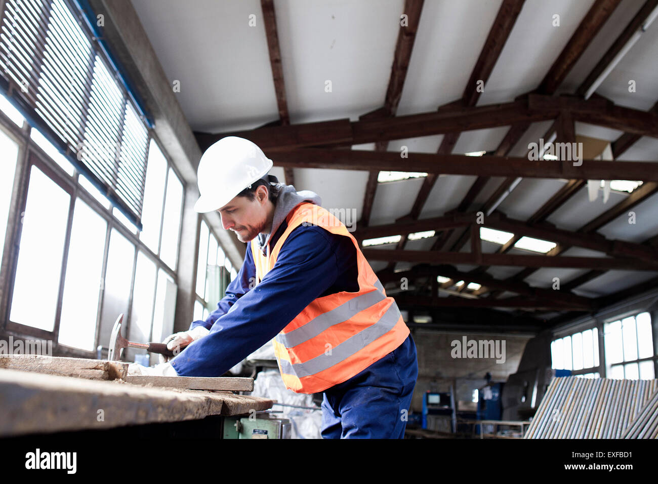 Factory worker hammering on workbench in concrete reinforcement factory ...