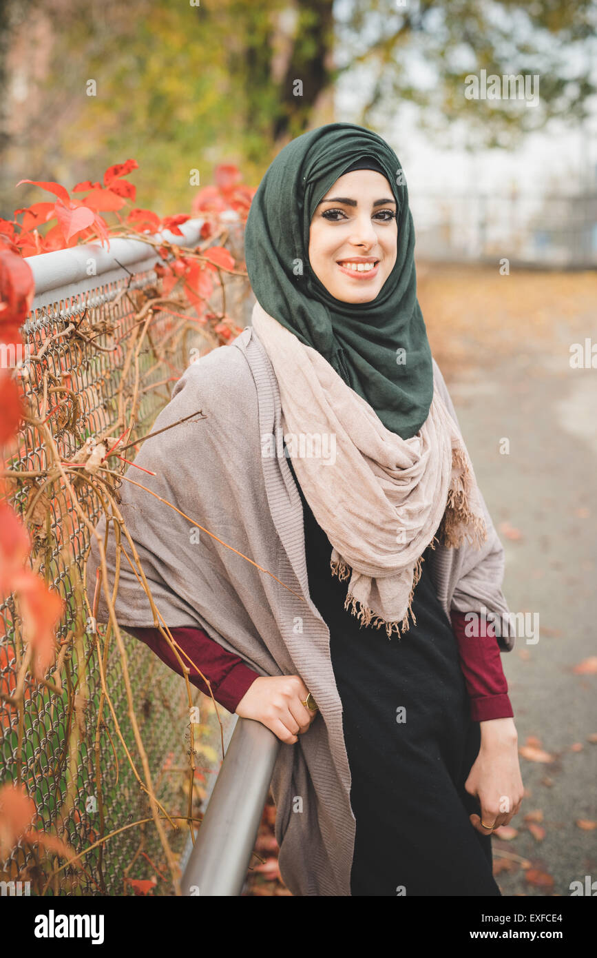 Portrait of young woman leaning against railing on park path Stock ...
