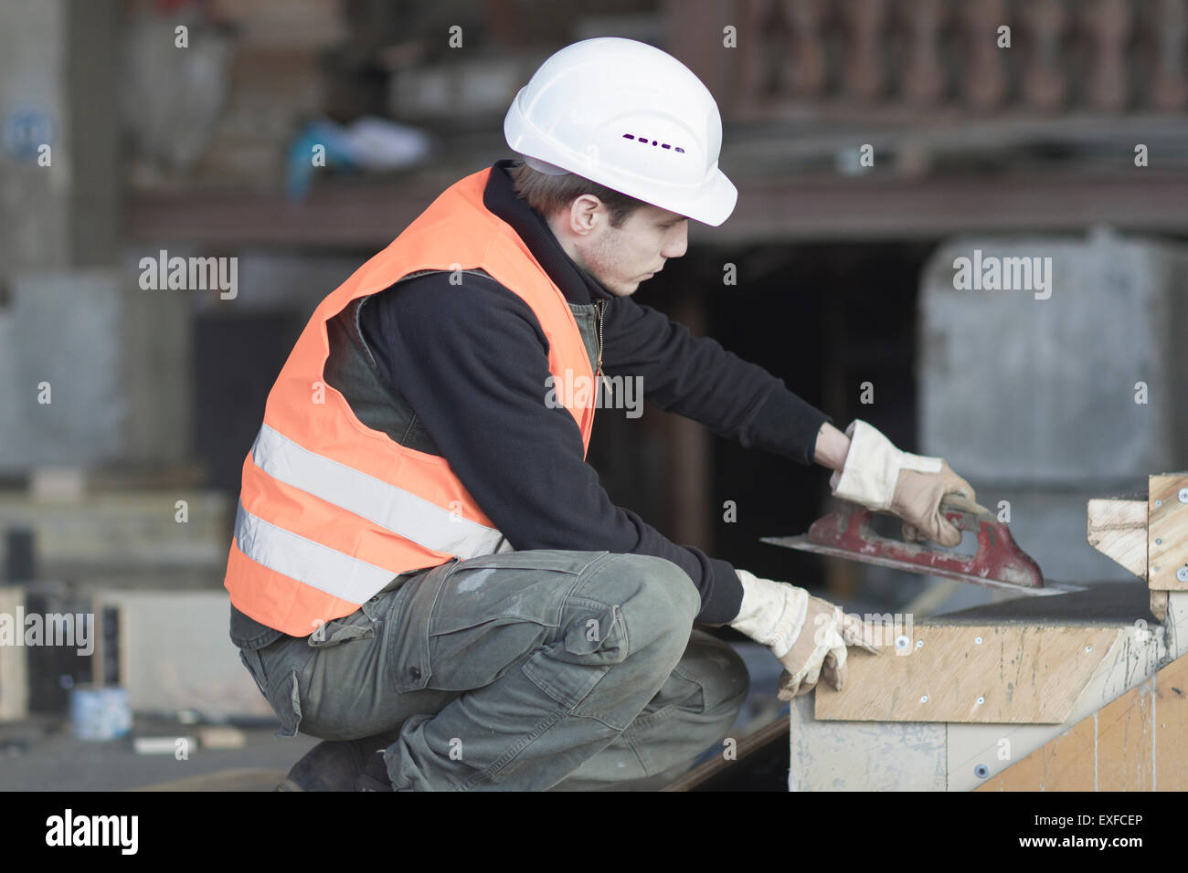 Factory worker using finishing trowel on concrete in concrete ...