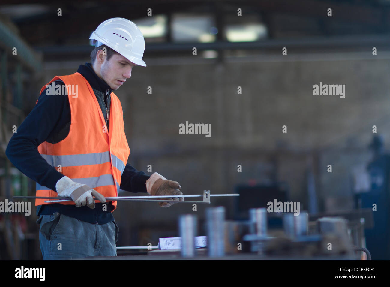 Factory worker selecting metal rod in concrete reinforcement factory ...