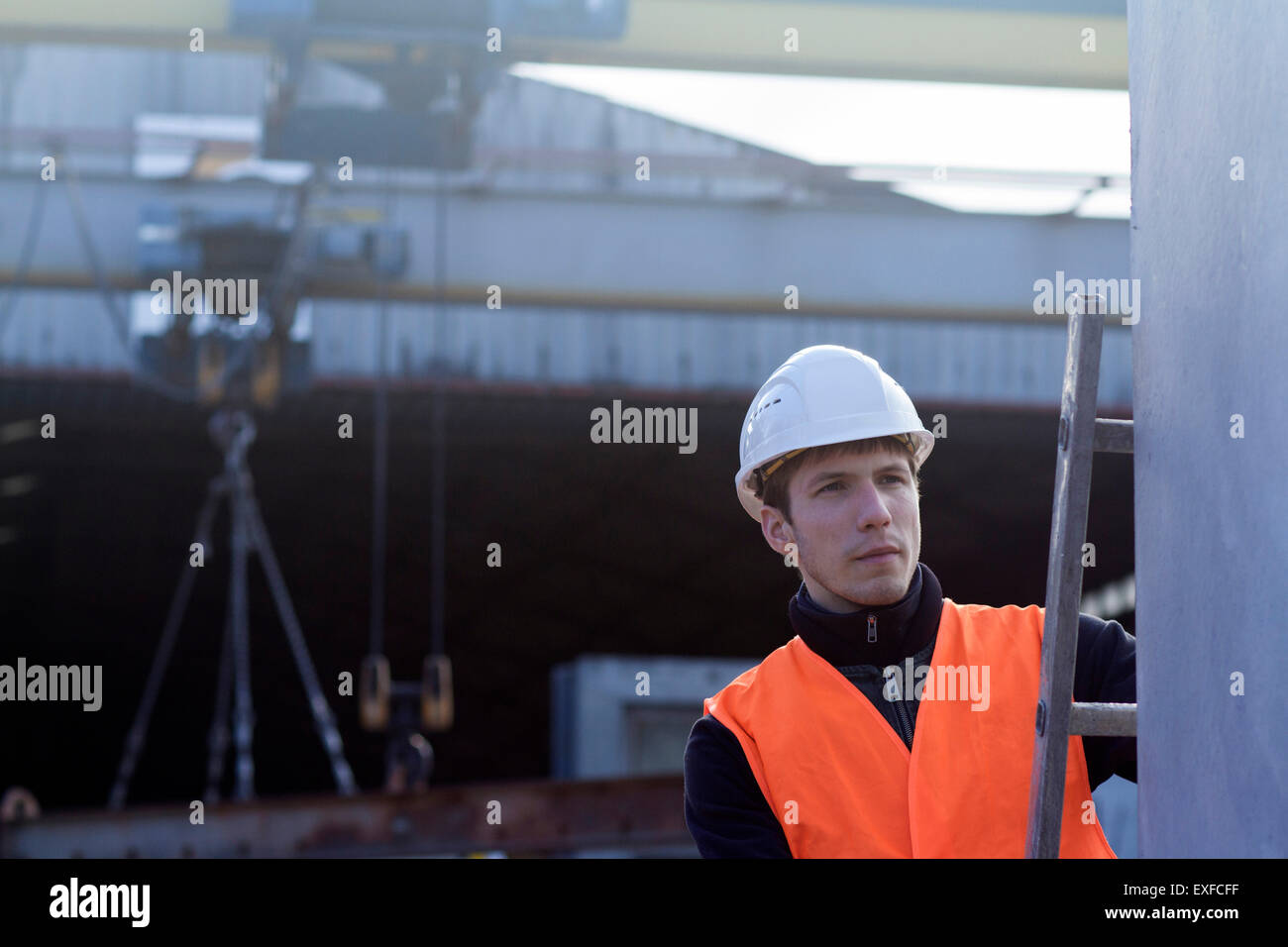 Factory worker on ladder checking concrete block in concrete ...