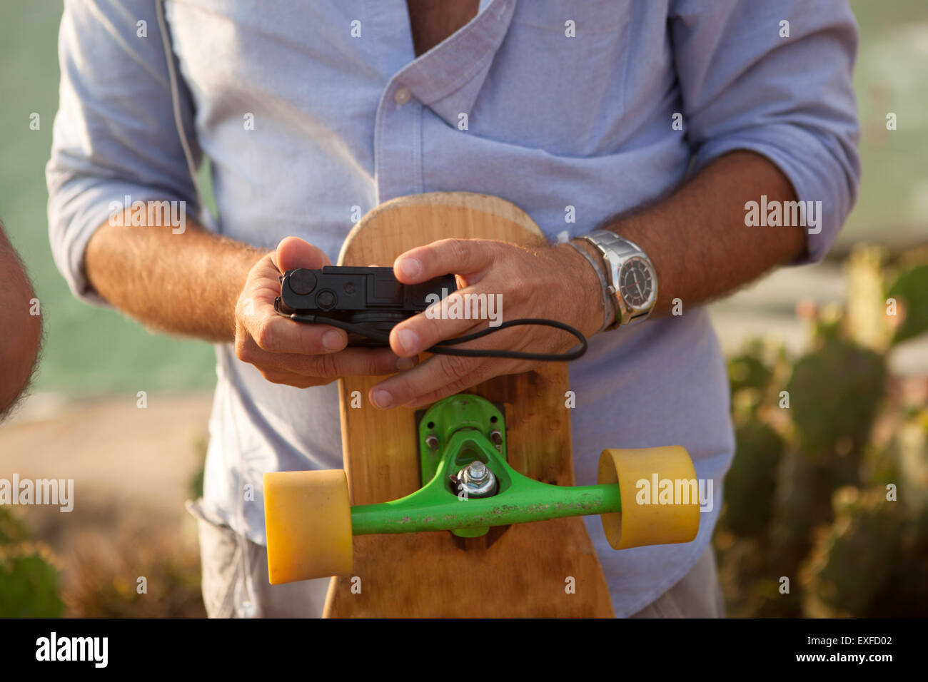 Man holding camera and skateboard Stock Photo - Alamy