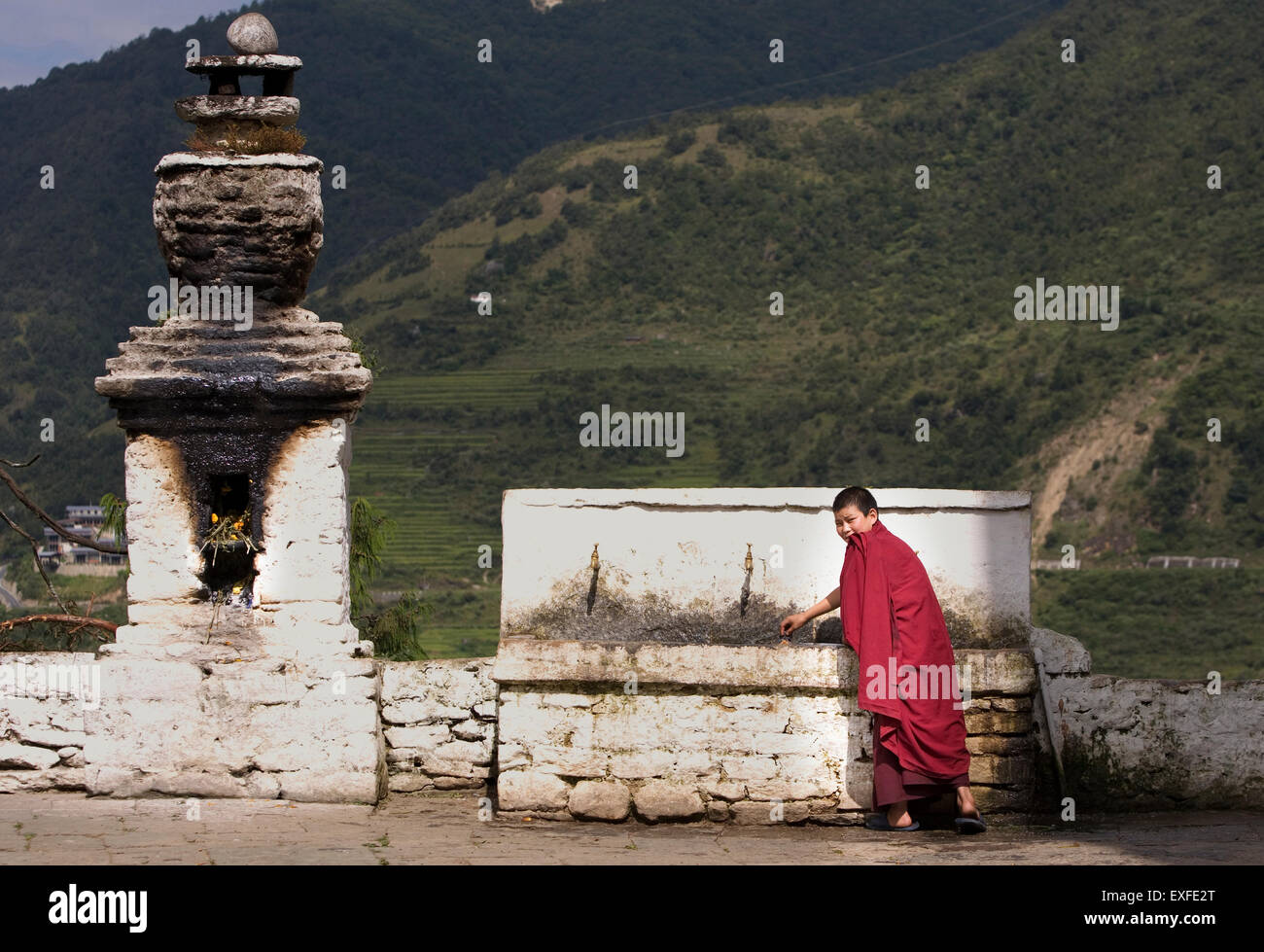 Portrait of young buddhist monk drinking at temple fountain, Punakha ...