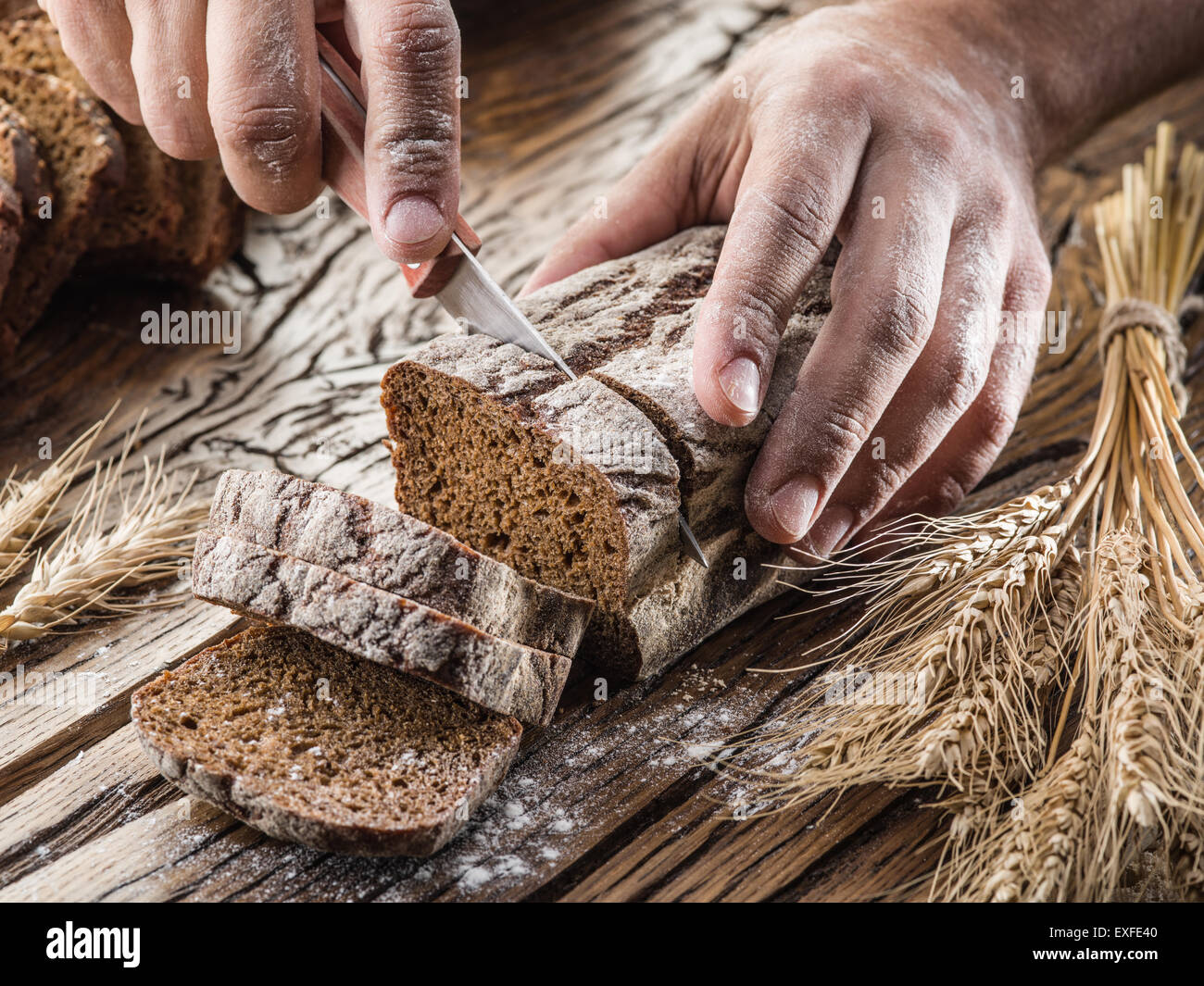 Man's hands cutting bread on the wooden plank Stock Photo - Alamy