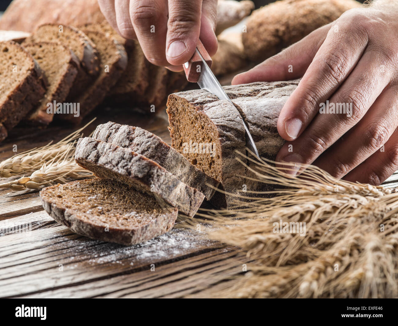 Man's hands cutting bread on the wooden plank Stock Photo - Alamy