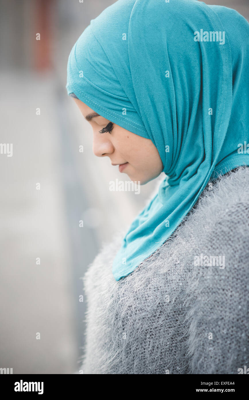 Close up portrait of young woman wearing turquoise hijab on footbridge ...