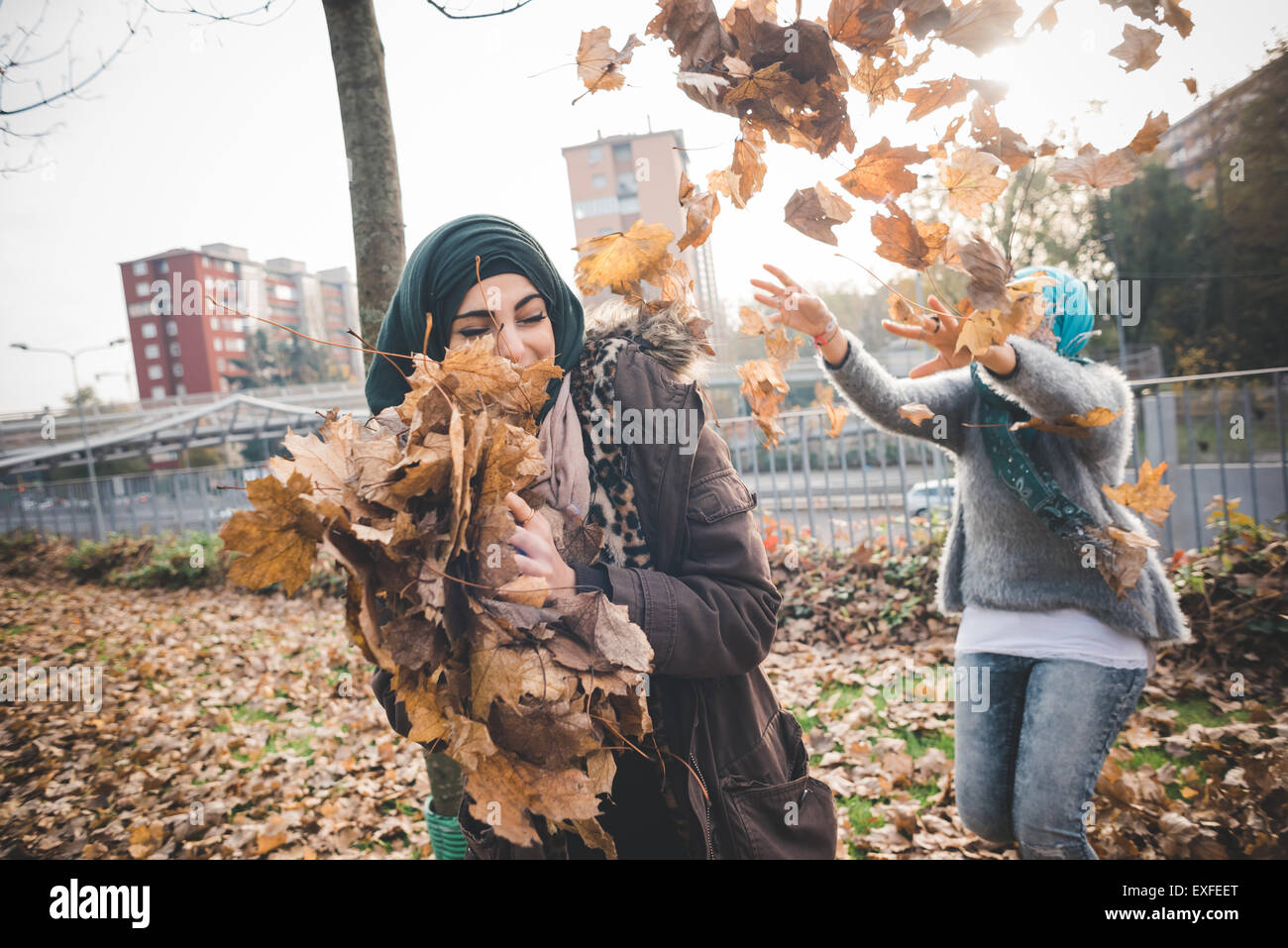 Two young women friends play fighting with autumn leaves in park Stock ...