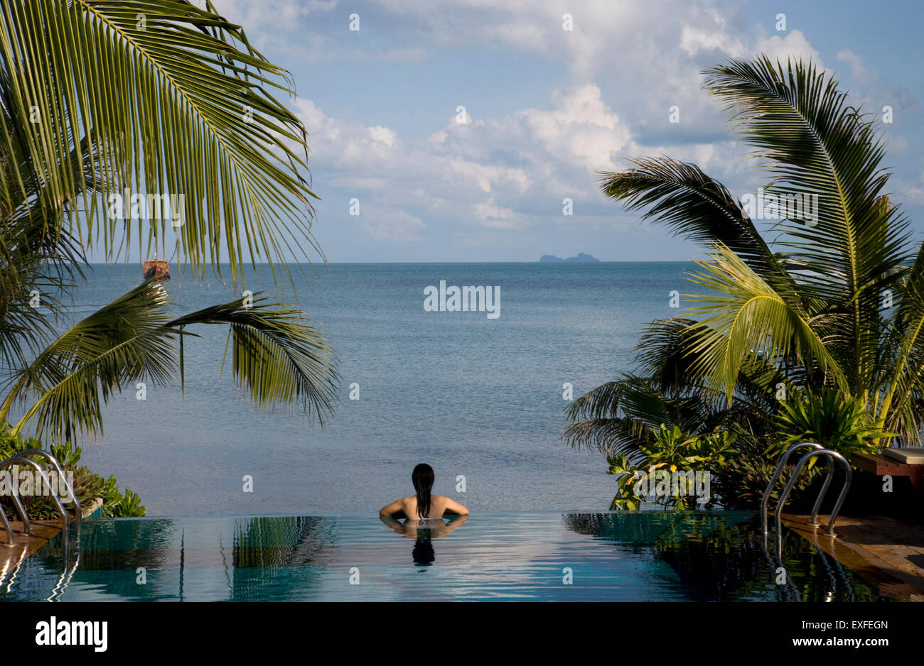 Rear view of mid adult woman relaxing in infinity pool, Koh Samui ...