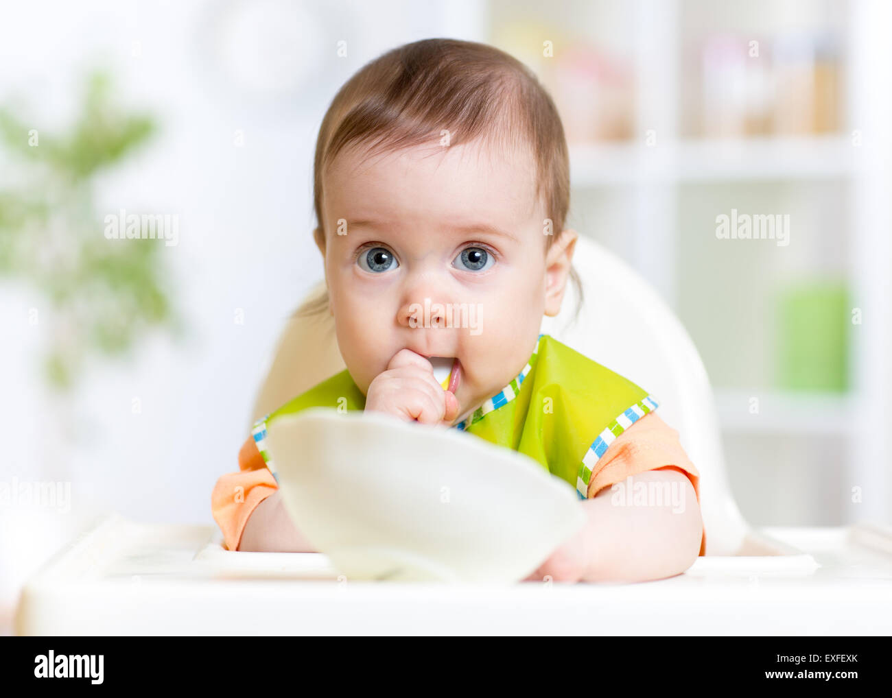 cheerful happy baby child sitting in chair with a spoon Stock Photo - Alamy