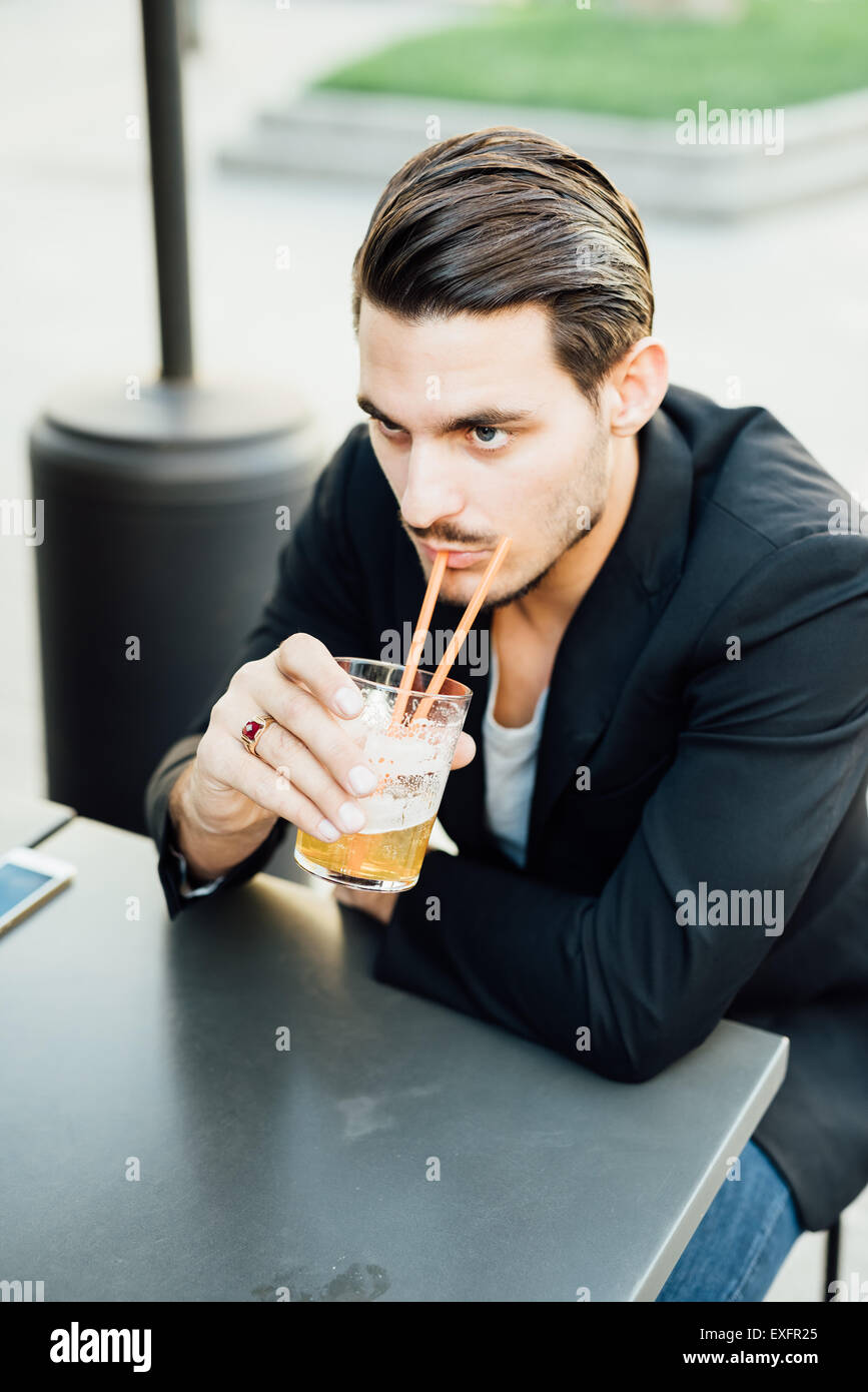 Young handsome italian boy having an happy hour seated on a bar in the ...