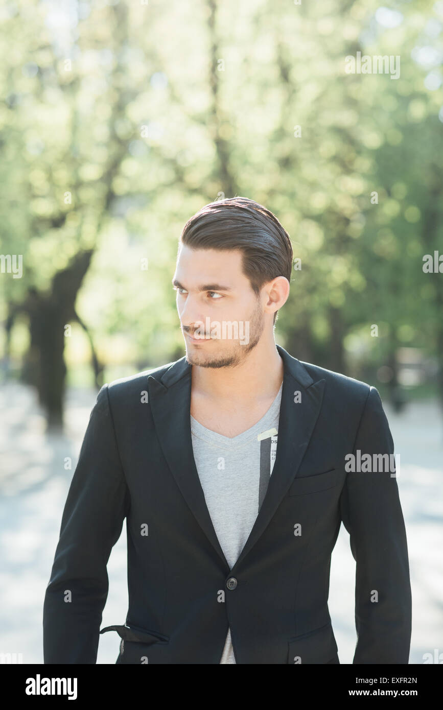Portrait of a young handsome italian boy posing in a park in the city ...