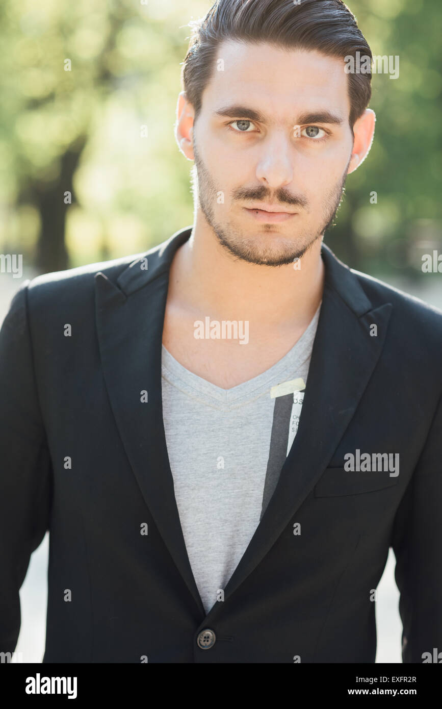 Portrait of a young handsome italian boy posing in a park in the city ...