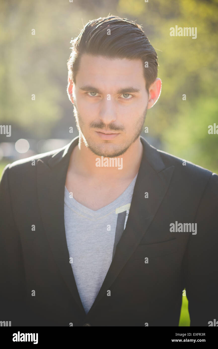 Portrait of a young handsome italian boy posing in a park in the city ...