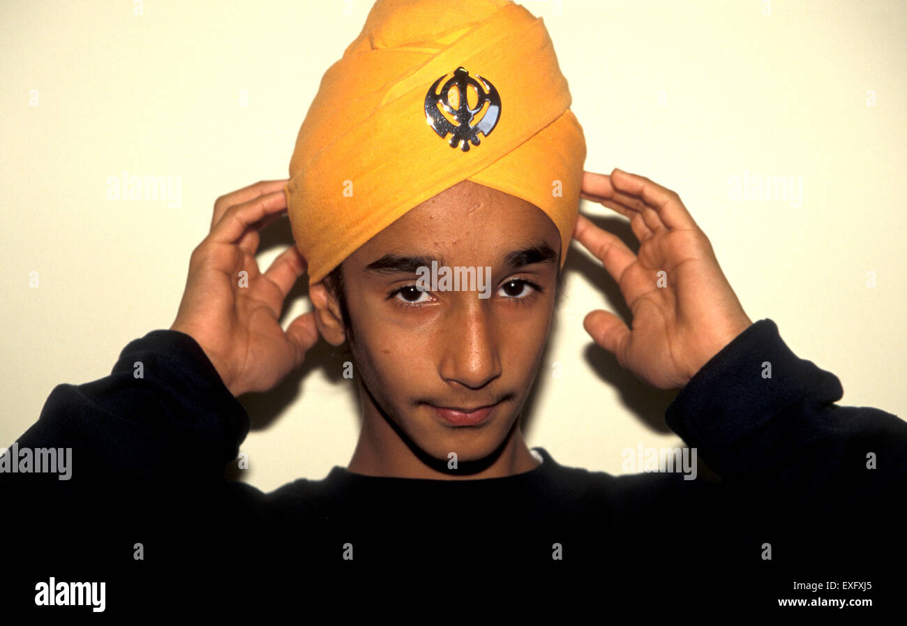 Sikh youth checking his turban which displays the symbol of the khalsa ...