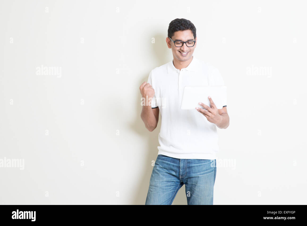 Portrait of excited Indian guy using tablet pc and celebrate his ...