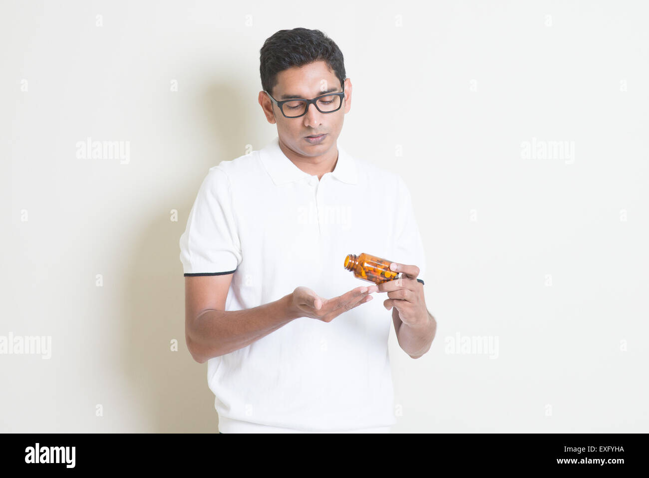 Sick Indian guy taking tablet medicine. Asian man standing on plain ...