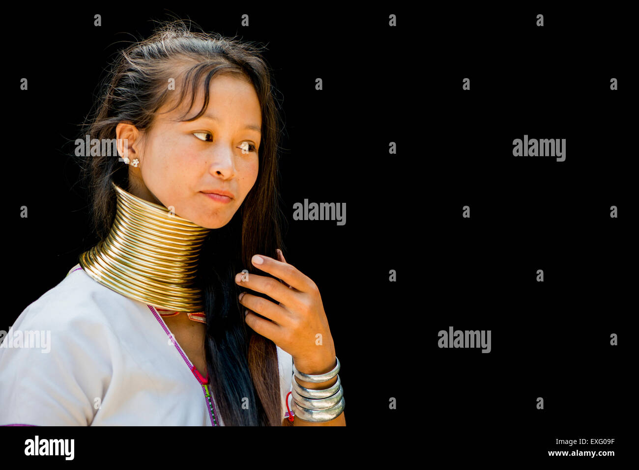 Young Kayan hill tribe woman doing her hair against a black background ...