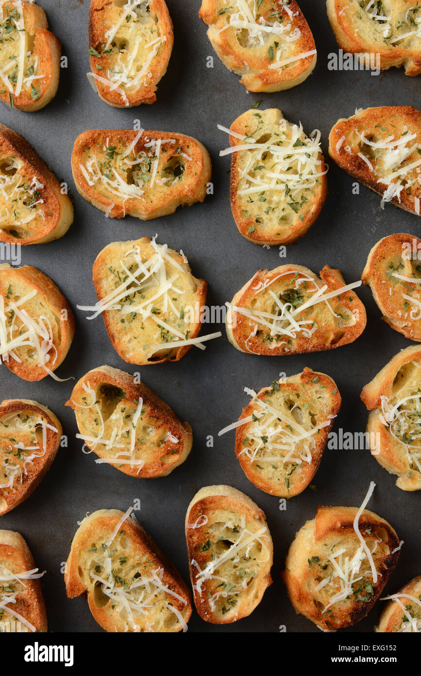Closeup of a pan full of toasted garlic bread. The bread slices have ...