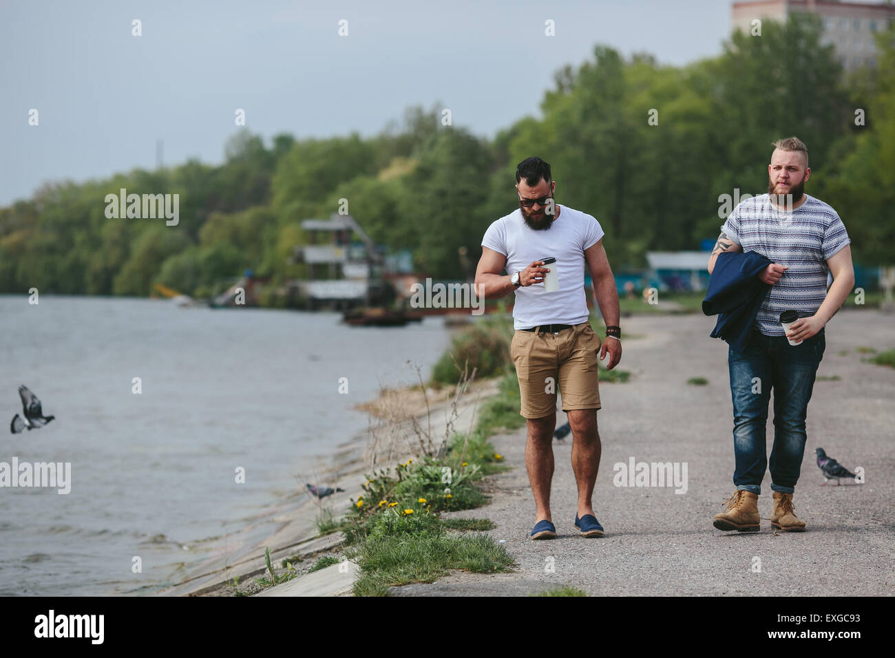 Two men walk and drink coffee Stock Photo - Alamy