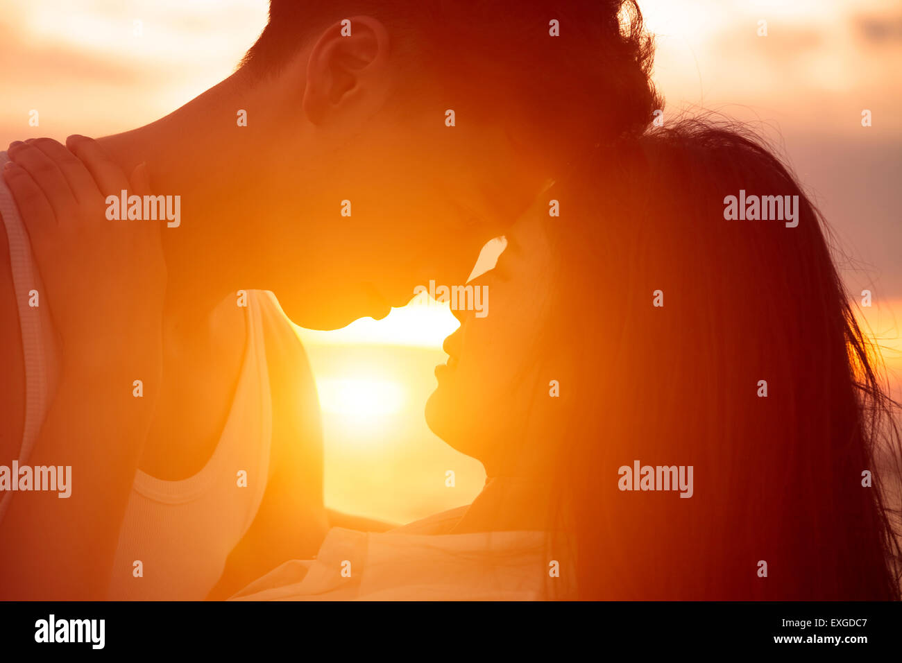 young couple kissing at sunset on beach Stock Photo - Alamy