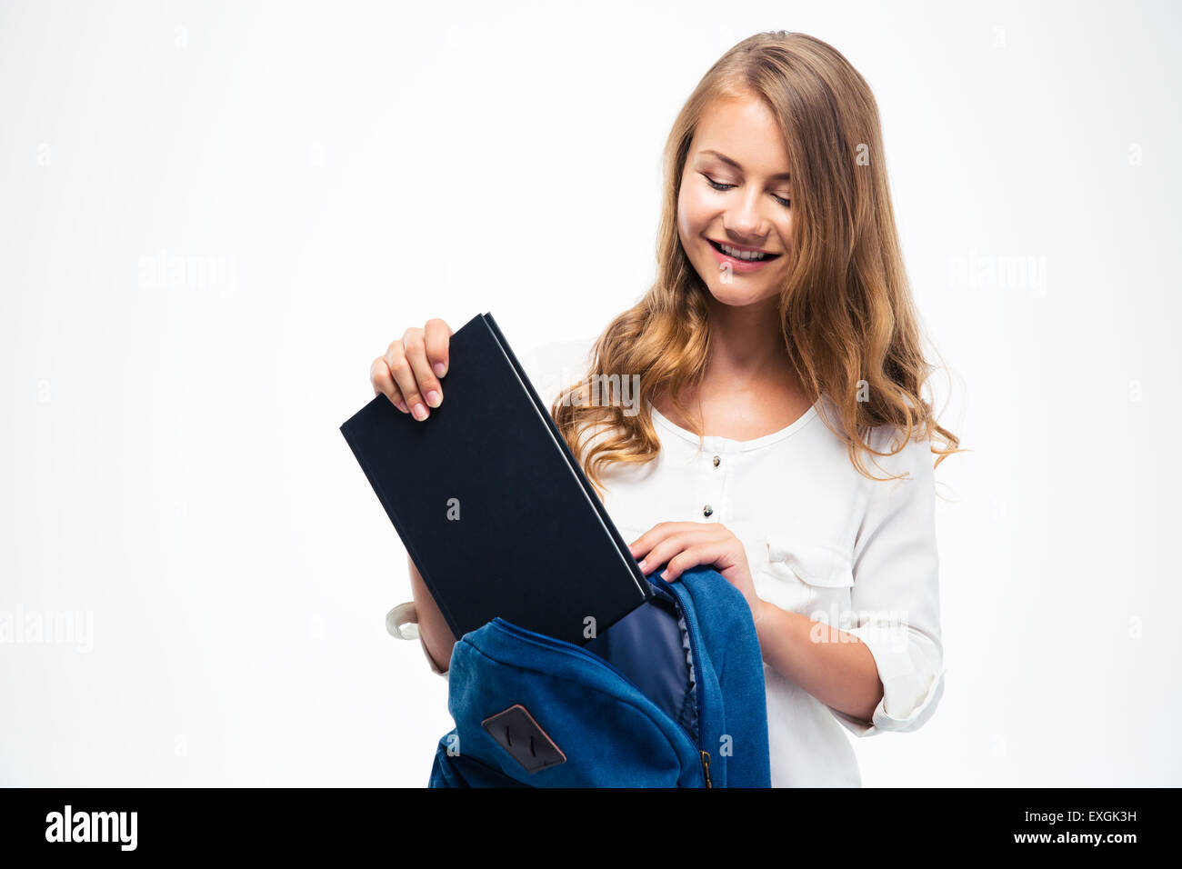 Happy young woman putting book into backpack isolated on a white ...