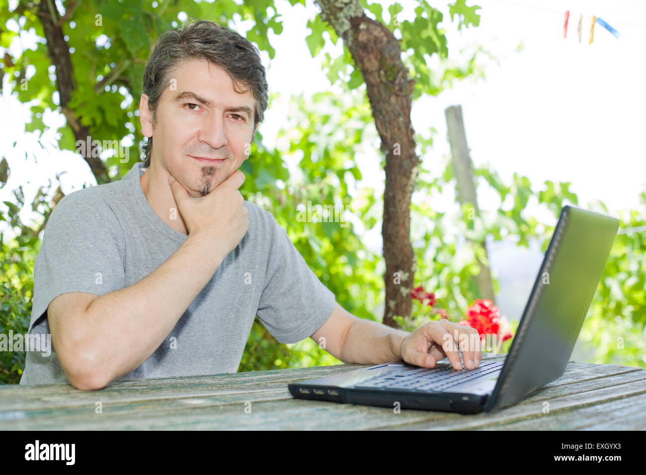 man sitting outdoor working with a laptop Stock Photo - Alamy