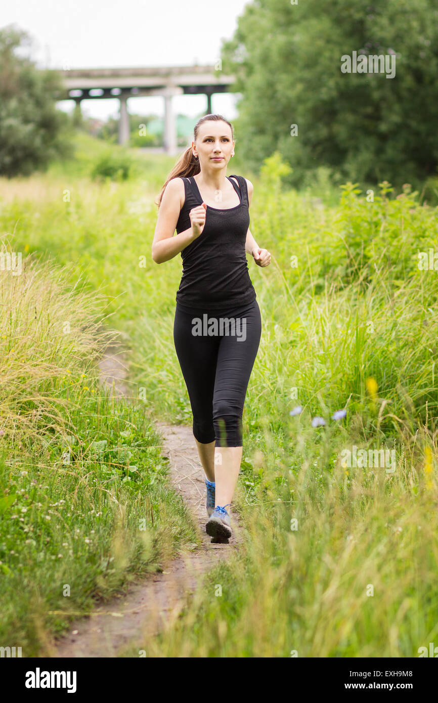 Jogging woman at summer midday. Sport fitness girl make exercises at ...