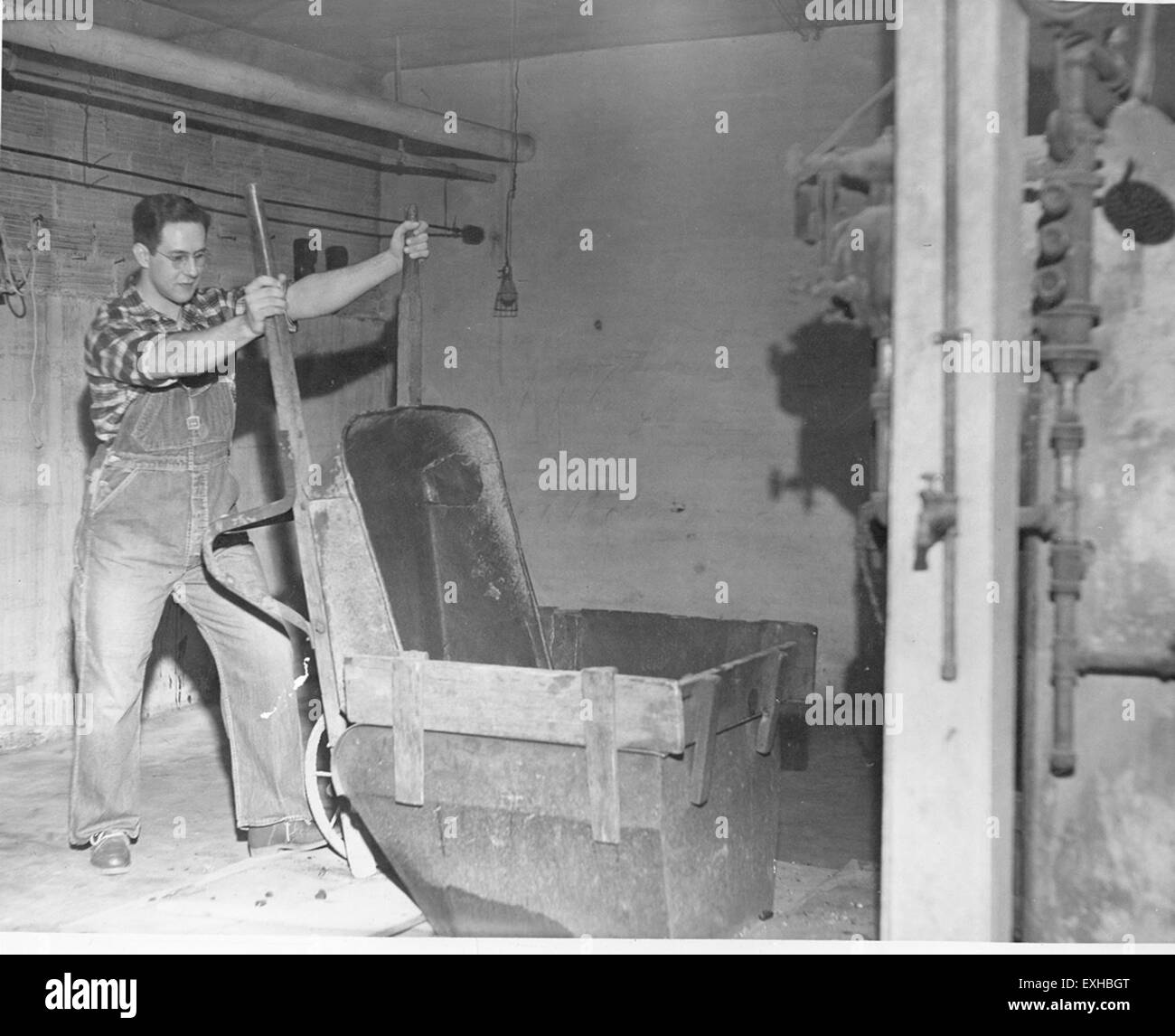 The image depicts a worker feeding a stoker, a device used in steam ...