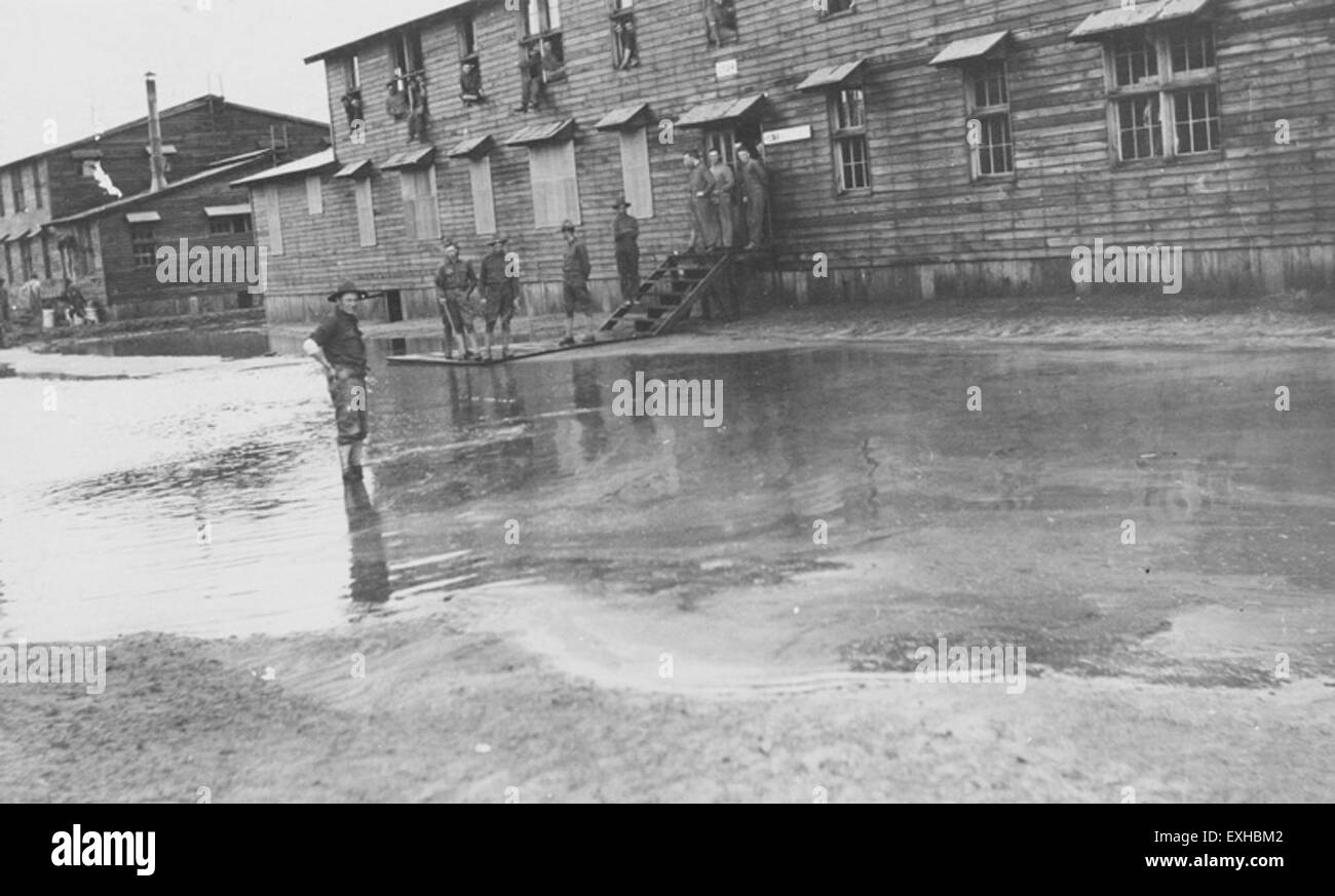 This photograph captures a flood occurring in front of the wooden ...