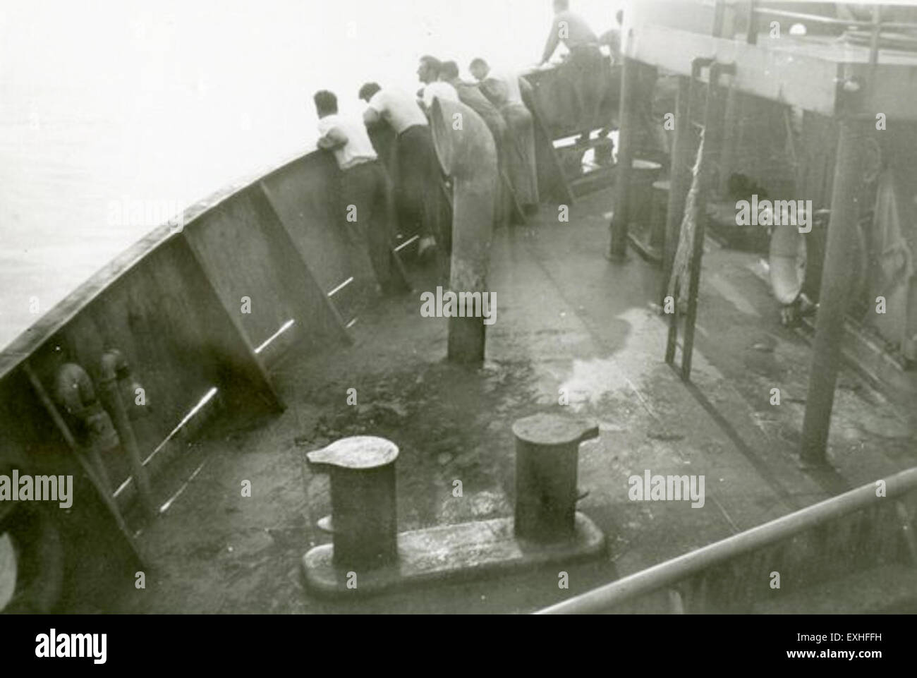 This image shows an individual leaning over the deck of a ship. The ...