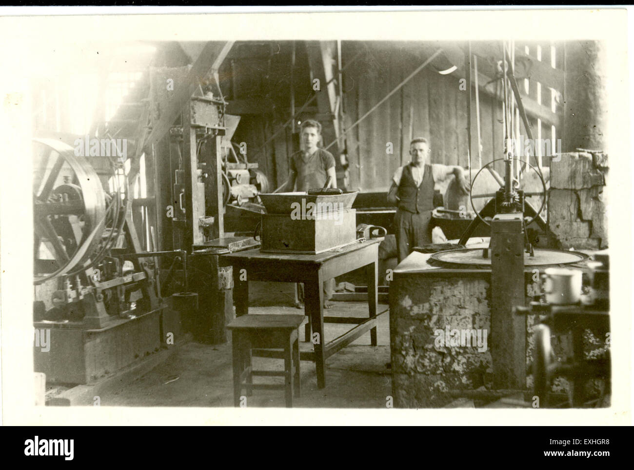 An industrial-era painting depicting men operating machinery. The piece ...