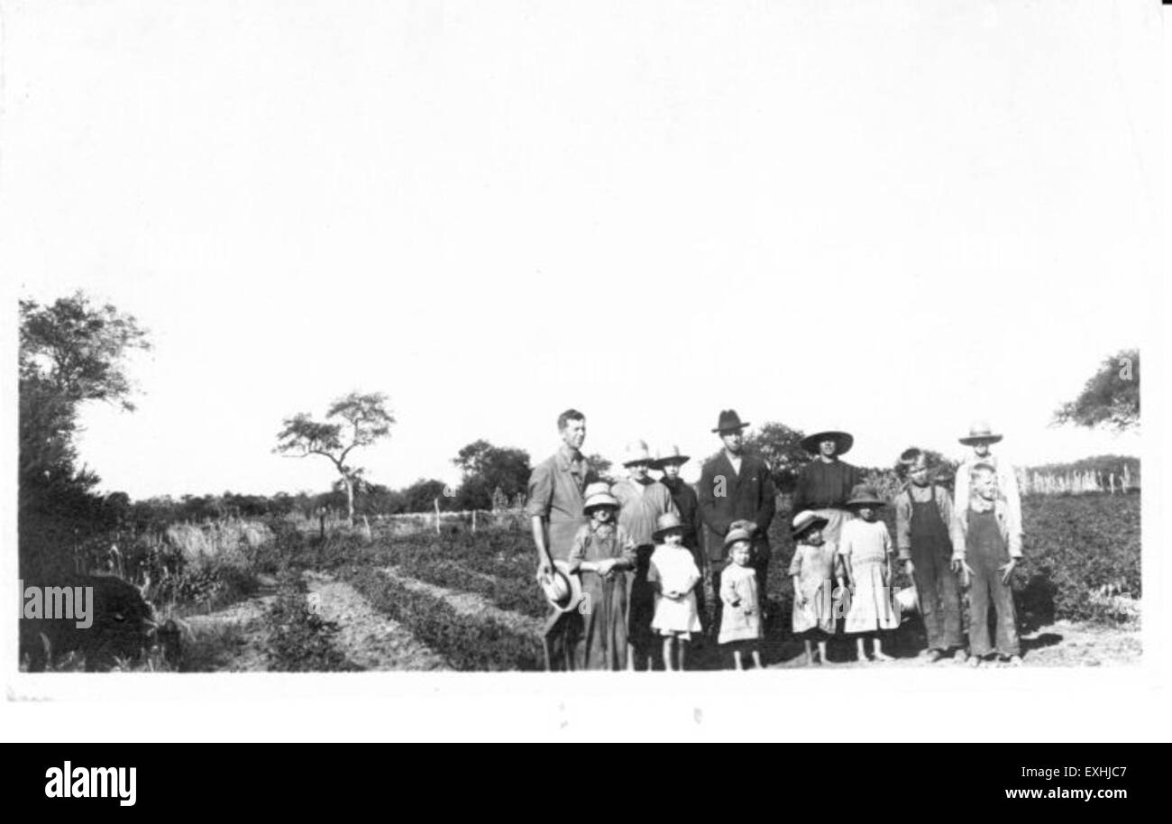 This photograph depicts a group of adults and children in a field ...