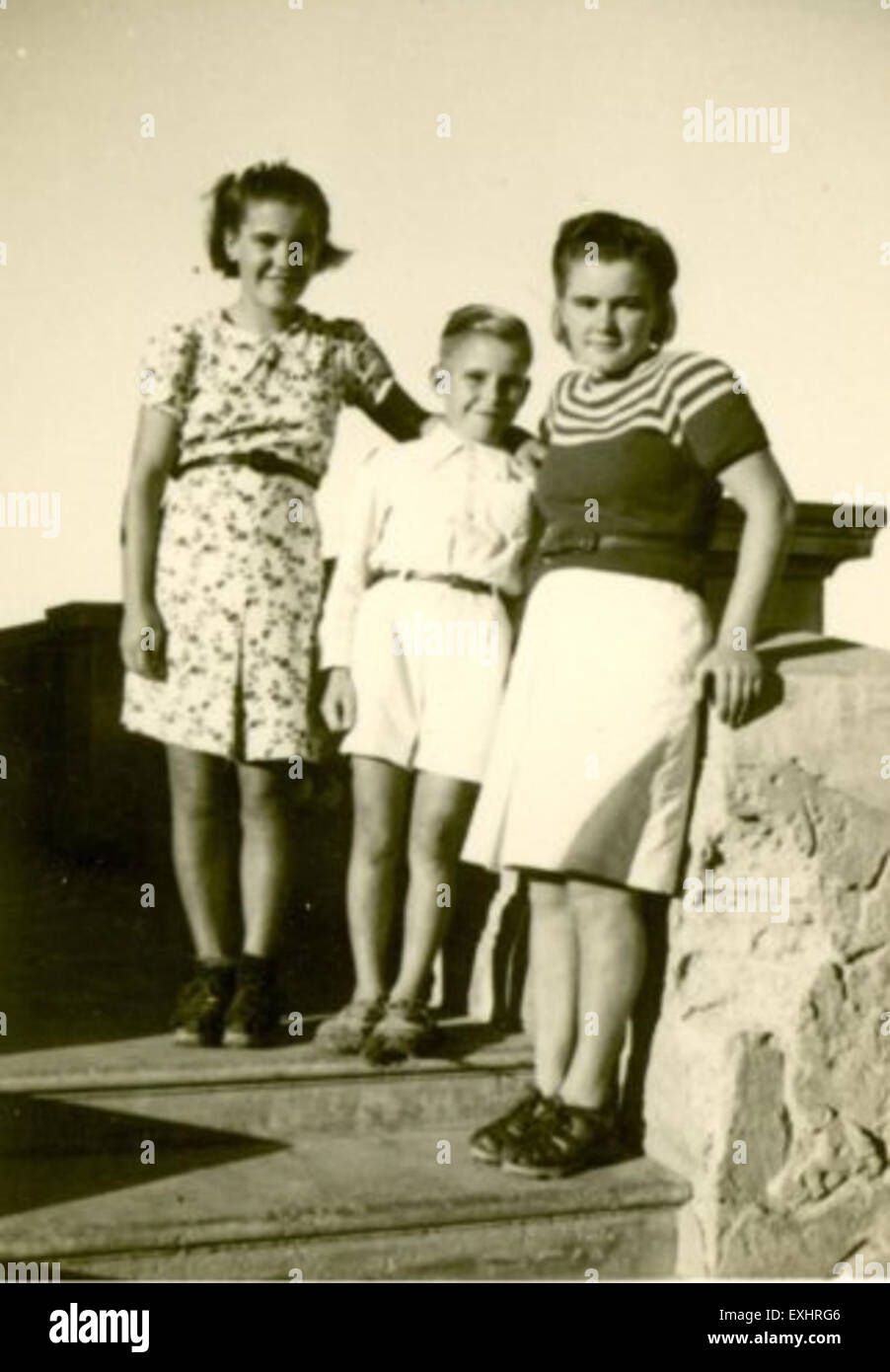 Three Children Leaning On Rocks Stock Photo - Alamy