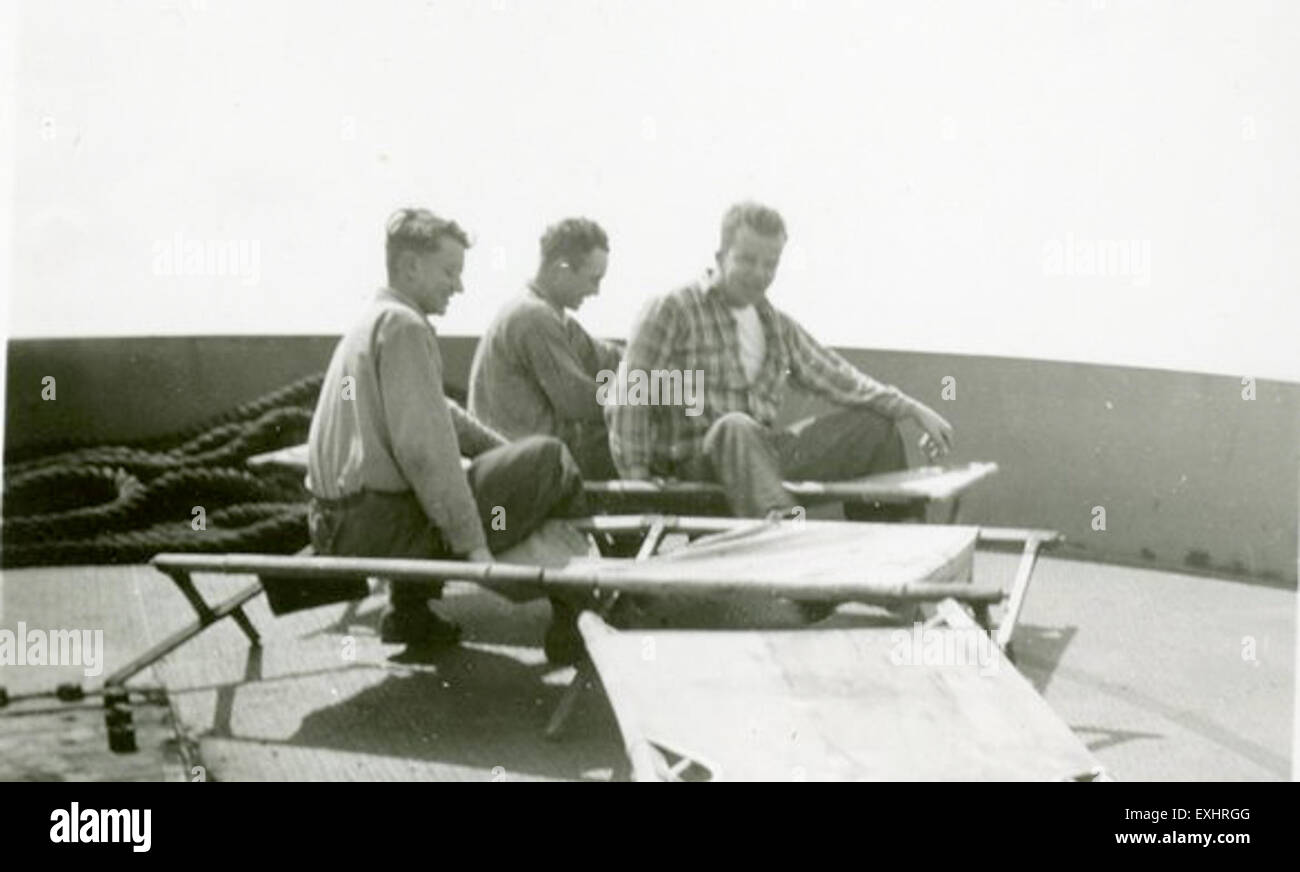 A photograph depicting three men on deck, possibly of a ship or boat ...