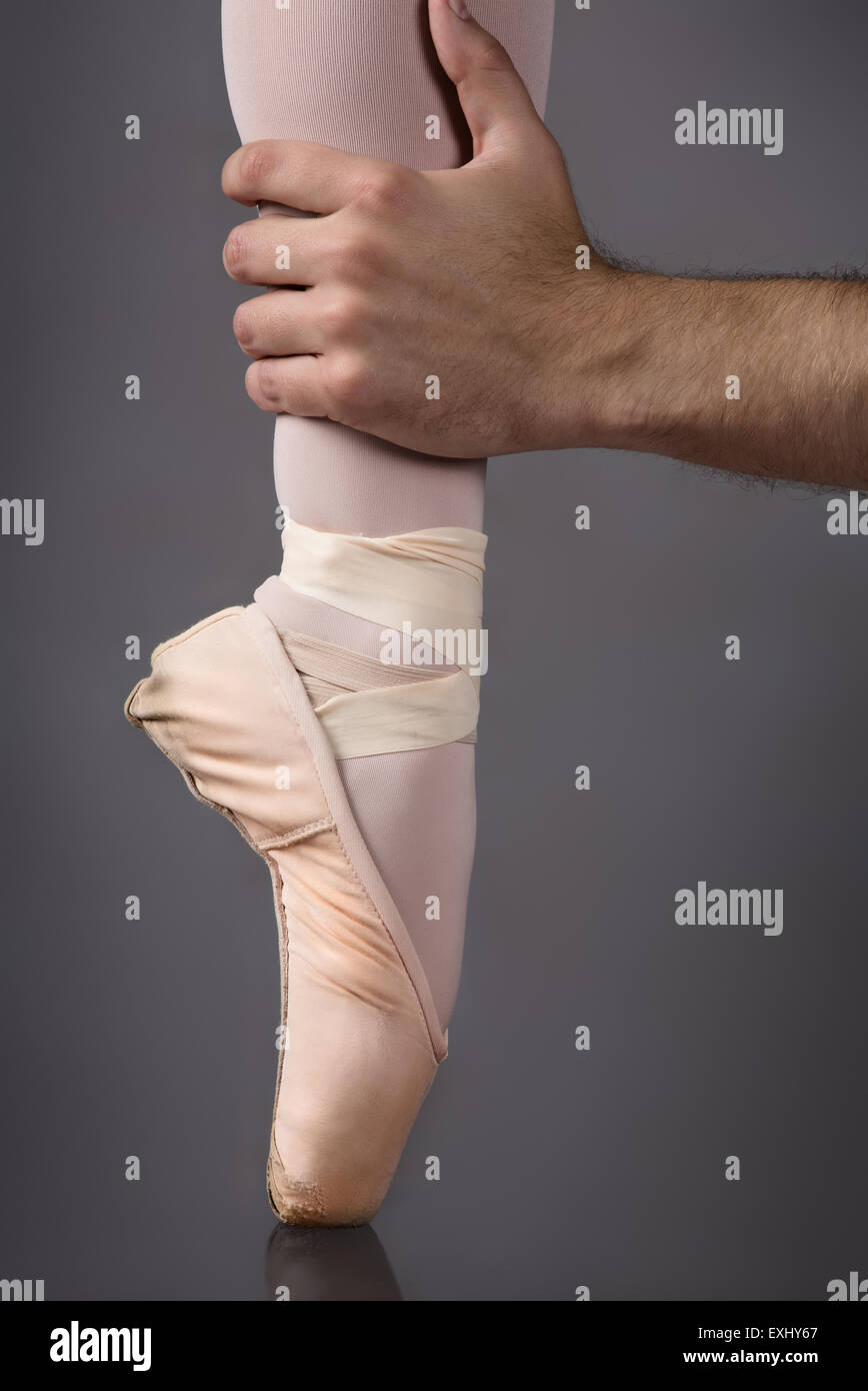 Male hand grasping the ankle of a female ballet dancer's foot in a pink ...