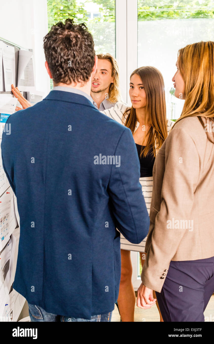 Businesspeople looking at bulletin board in office Stock Photo - Alamy