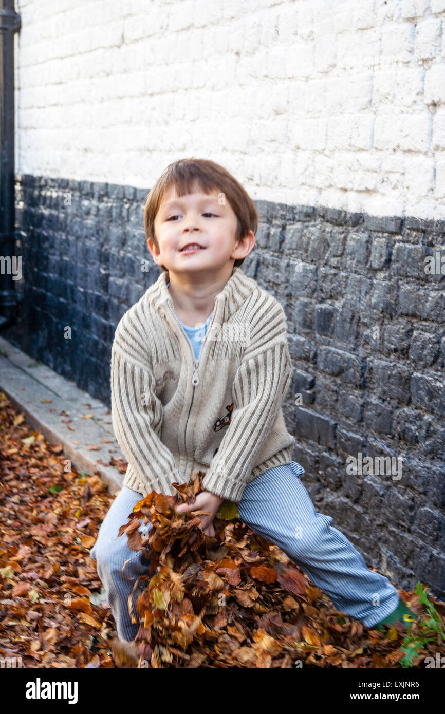 3 to 5 year old Caucasian boy, outdoors. crouching down and grabbing ...