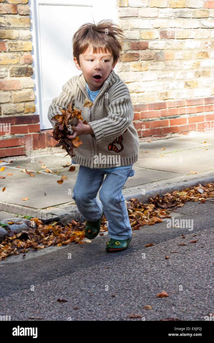 Caucasian child, boy, 6-7 years old, walking along a street with piles ...