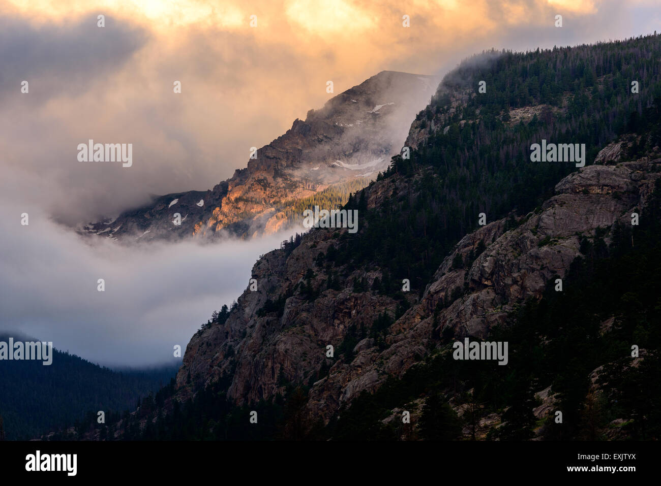 Sun shining through the clouds and fog lighting the mountains by ...