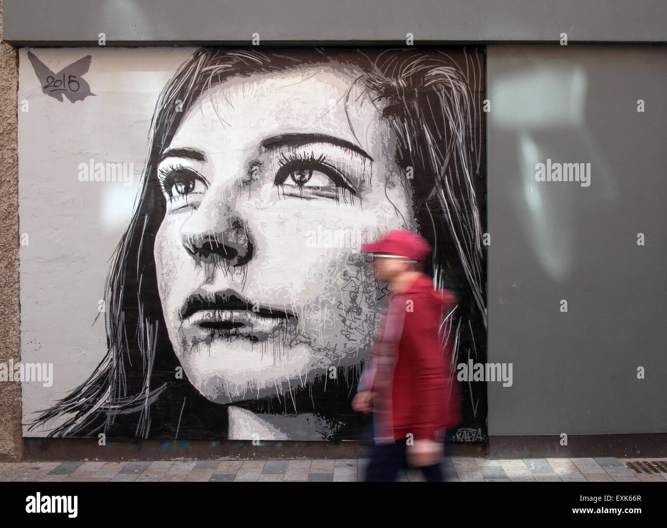Woman in black walking past colourful graffiti hi-res stock photography ...