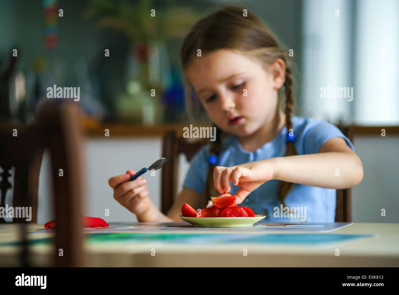 Cute little girl tasting strawberry at home, indoor Stock Photo - Alamy