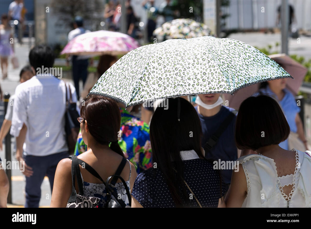 Pedestrians hold parasols to get some shade in the hot weather in ...