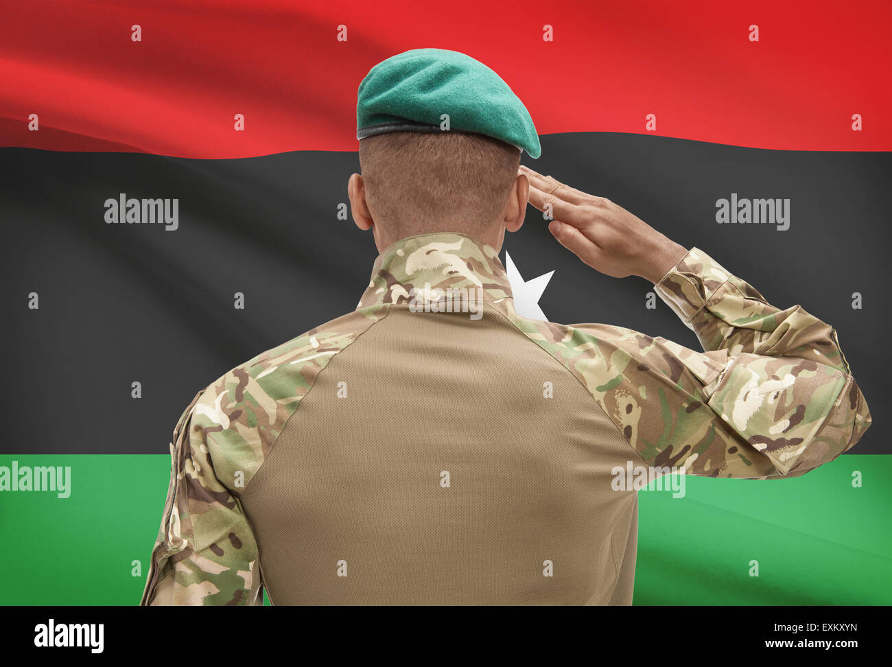 Dark-skinned soldier in hat facing national flag series - Libya Stock ...