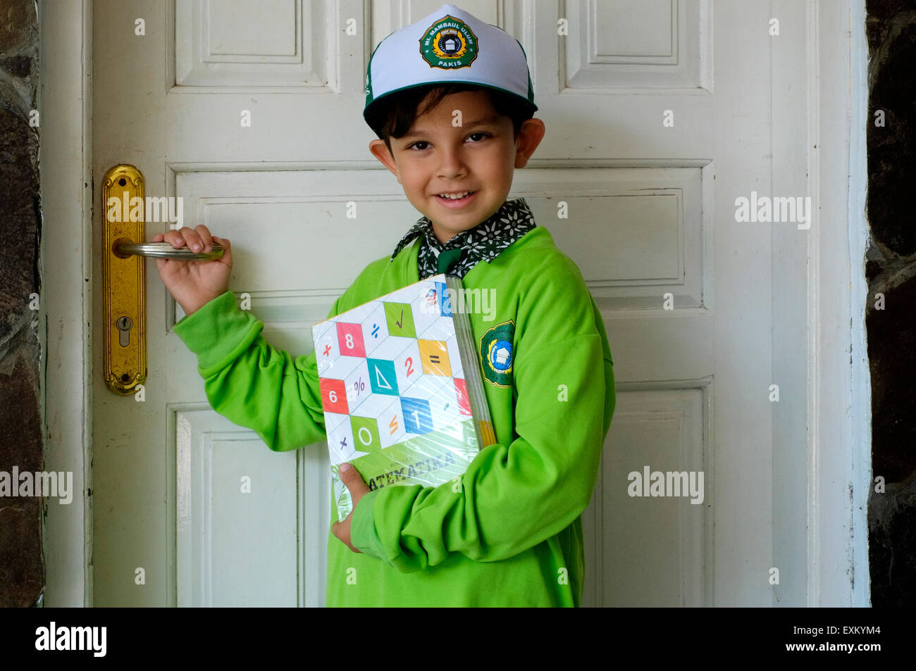 little boy dressed in his school uniform arrives home carrying his ...